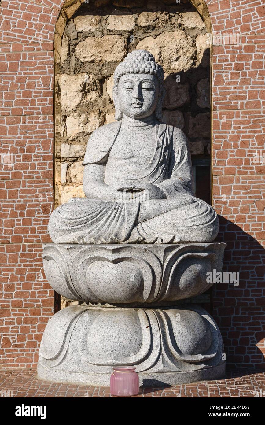 White stone statue of a Buddha on masonry background Stock Photo - Alamy