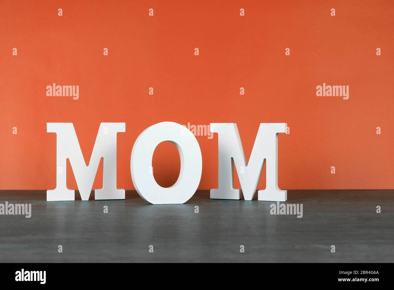 The word mom written in white letters in front of orange background ...