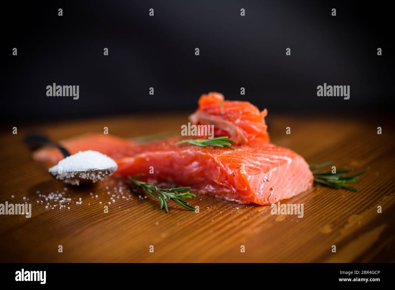 salty red fish on a fork, wooden background Stock Photo - Alamy