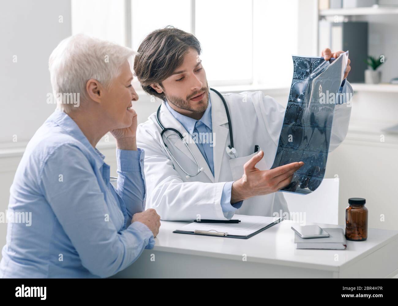 Doctor showing x-ray scans of head to senior female patient Stock Photo ...