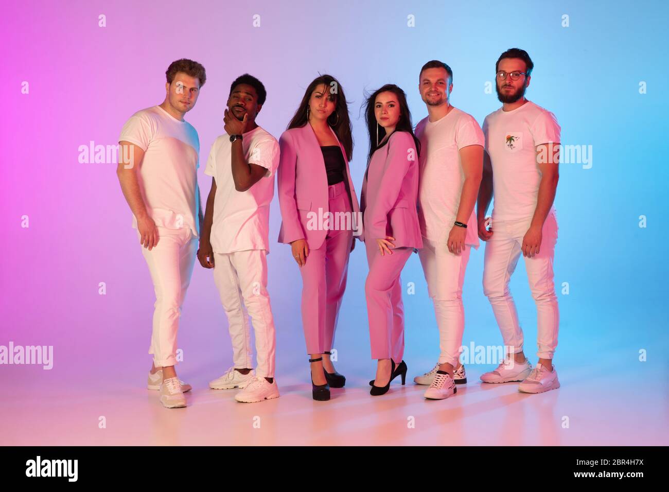 Group of young multiethnic musicians created band, posing in neon light ...