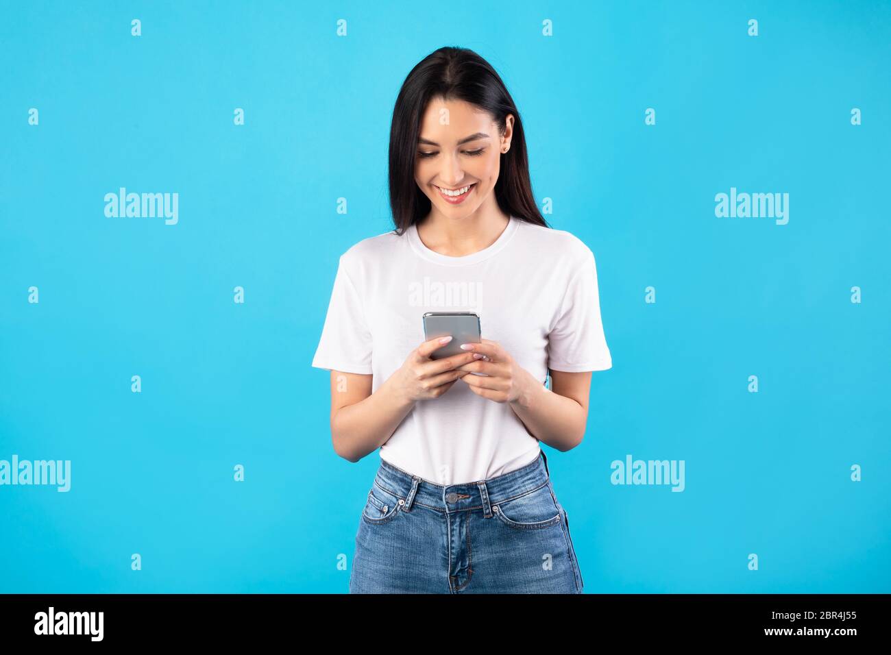 Happy girl using mobile phone at studio Stock Photo - Alamy