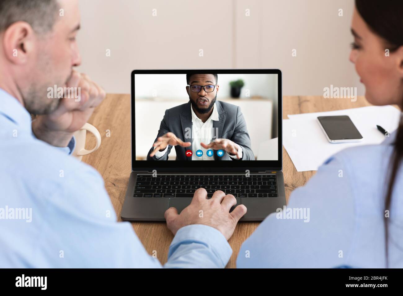 Workers having discussion during video call with colleague Stock Photo ...
