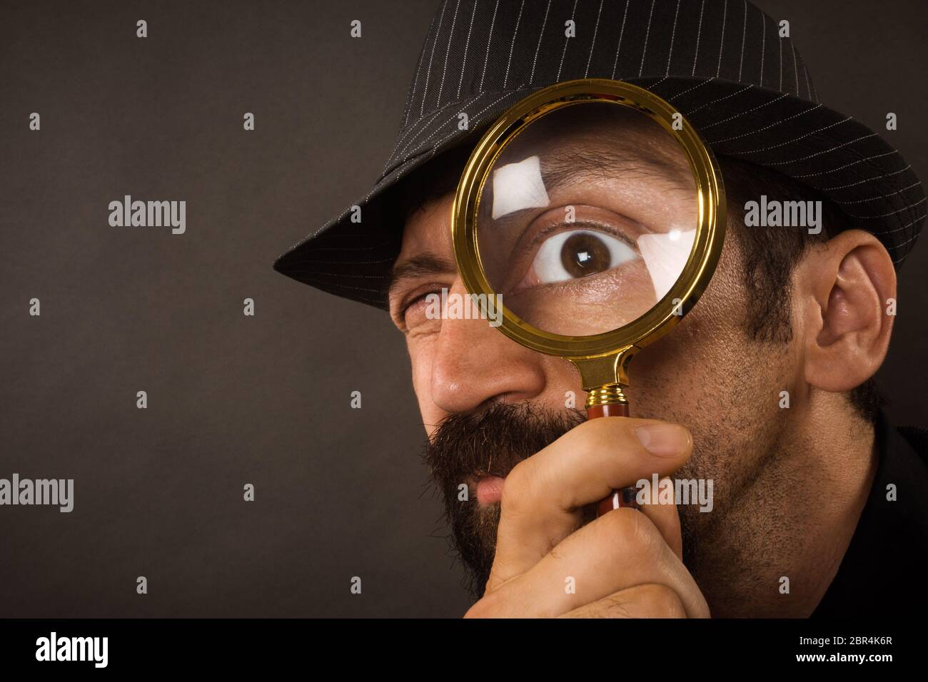 The curious detective is looking with magnifier or magnifying glass or ...