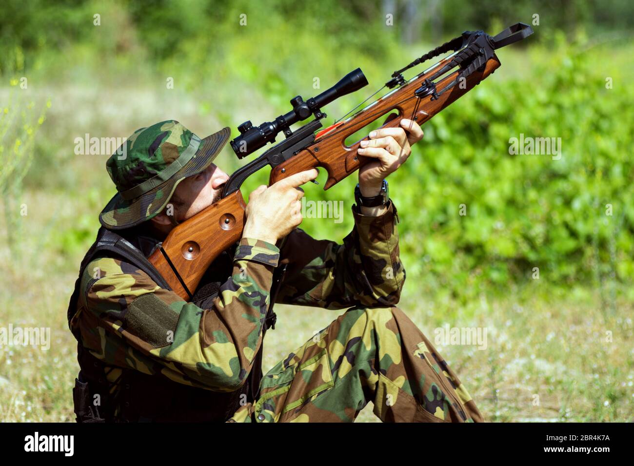 The soldier in military uniform is aiming and shooting with crossbow ...