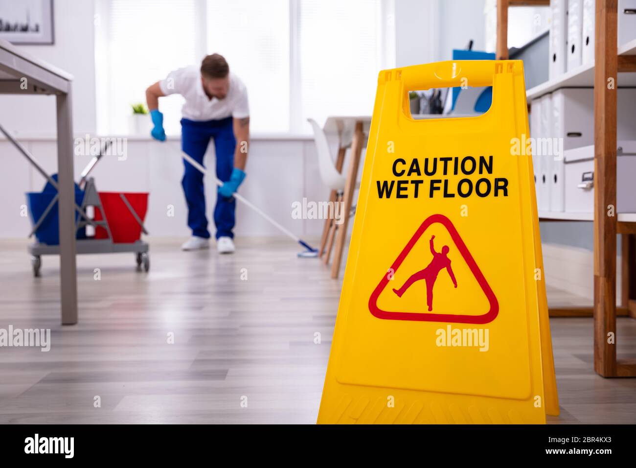 Male janitor with mop cleaning modern office floor Stock Photo - Alamy