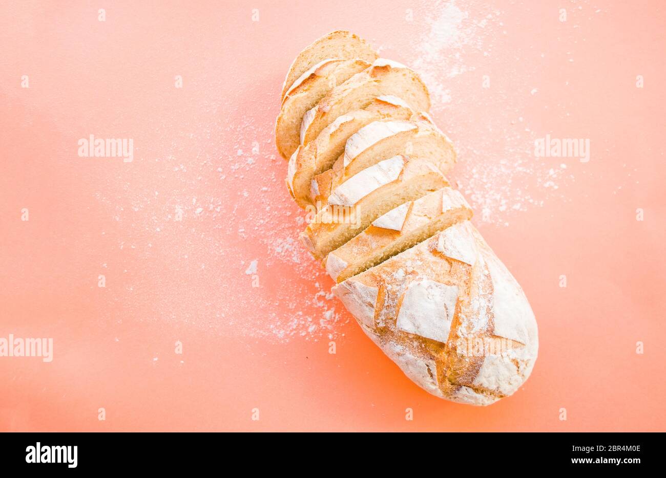 Freshly backed wholegrain sliced bread covered with flour on orange ...