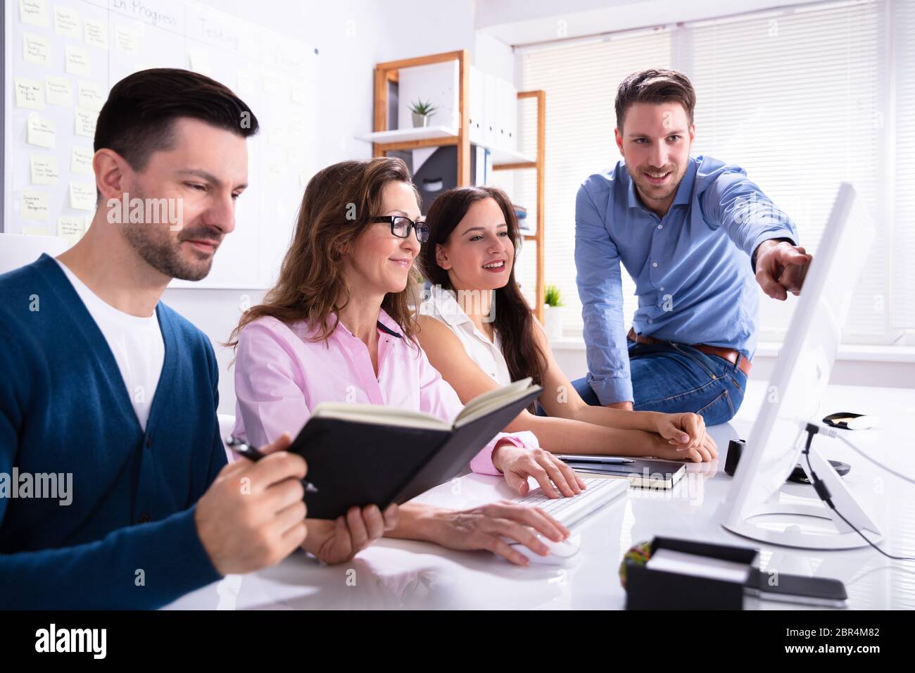 Young Businessman Explaining Plan To Colleagues On Compute At Workplace ...