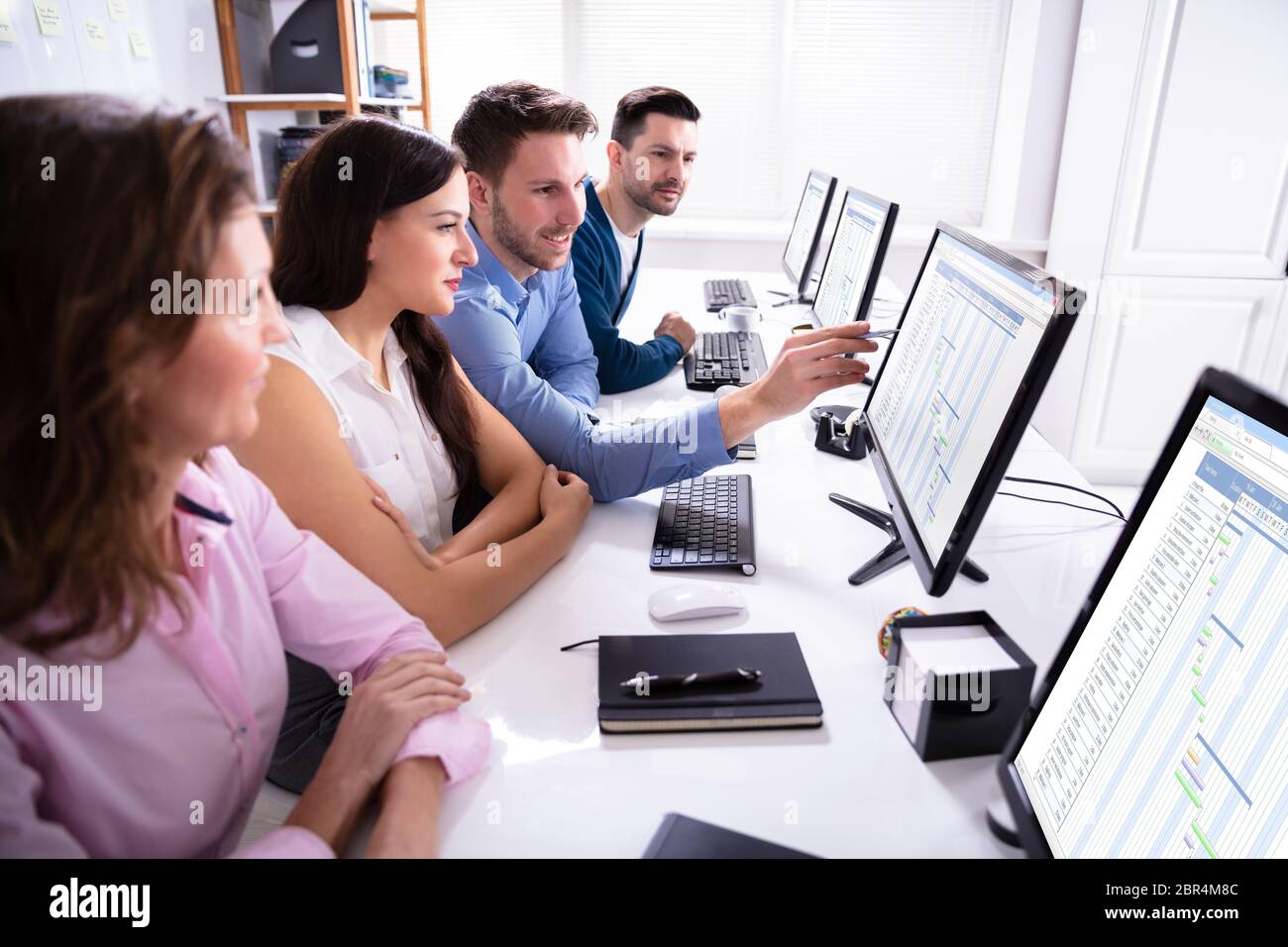 Young Businesspeople Analyzing Gantt Chart On Computer At Workplace ...