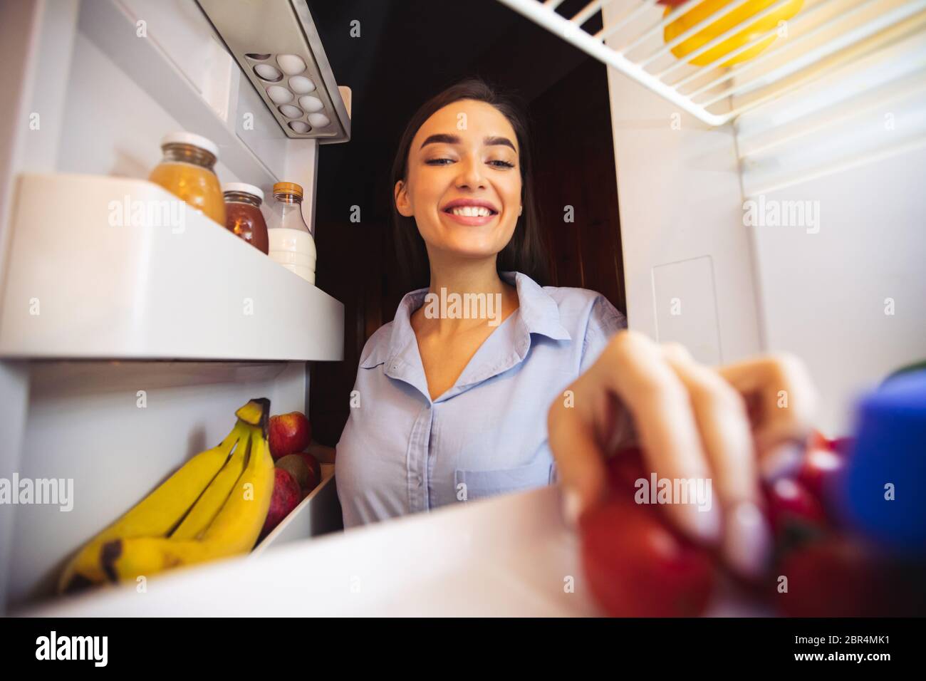 Young woman taking food from her fridge at home Stock Photo - Alamy