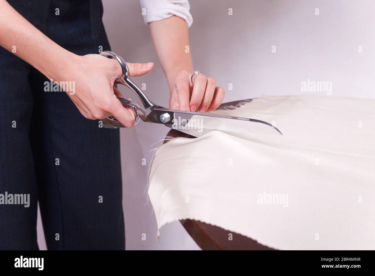 Seamstress cuts fabric with tailor's scissors Stock Photo - Alamy