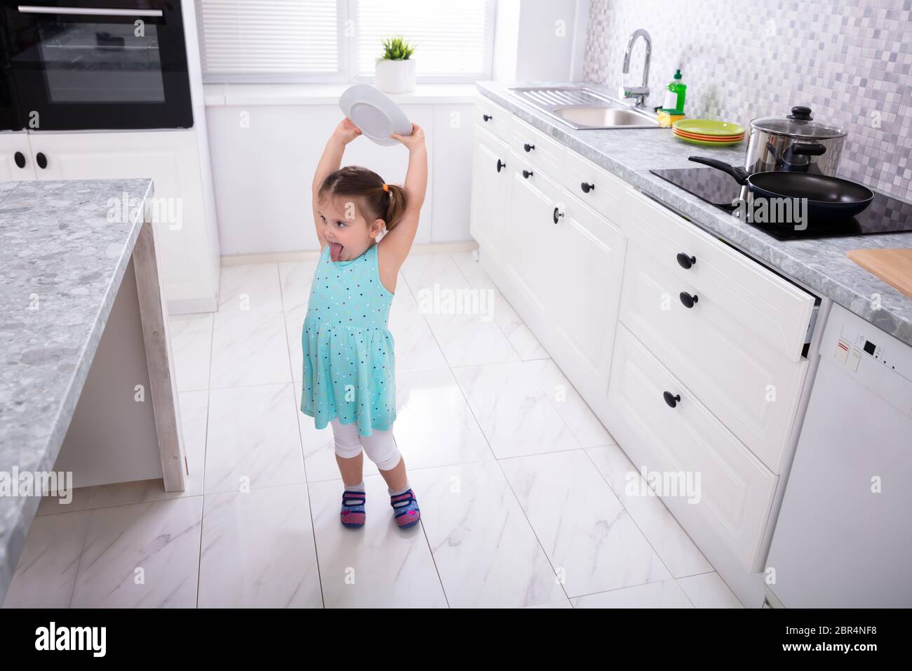 Pretty Girl Throwing White Plate In Kitchen Stock Photo - Alamy