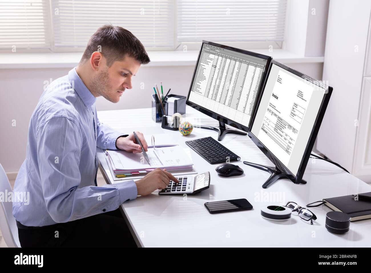 Young Businessman Calculating Invoice On Computer Screen Using ...