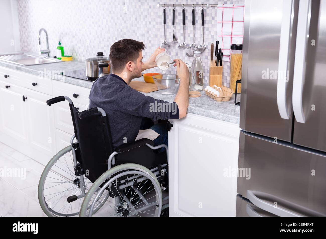 Young Disabled Man Sitting On Wheel Chair Preparing Food In Kitchen ...
