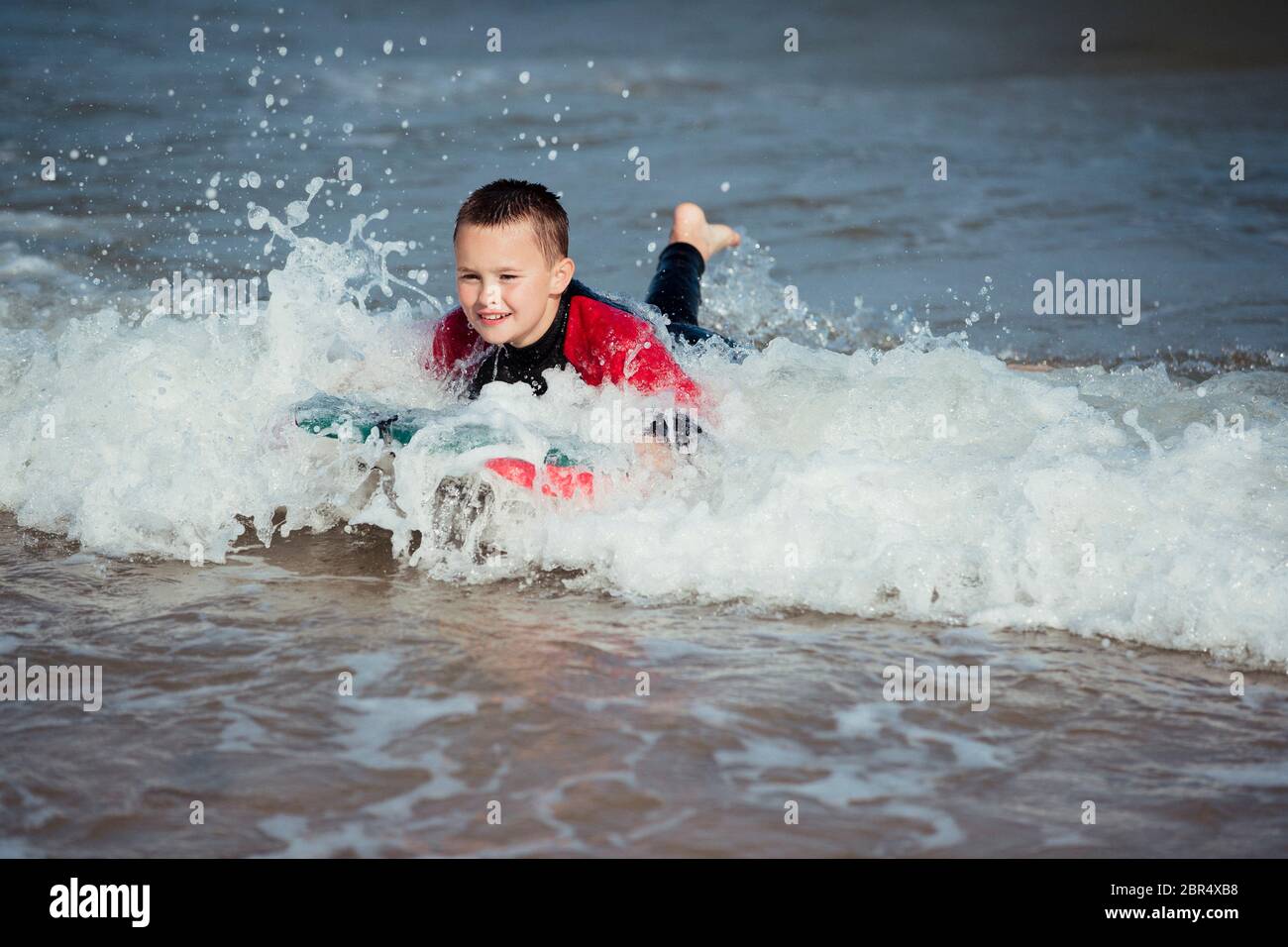 Little boy playing in the surf with a bodyboard Stock Photo - Alamy