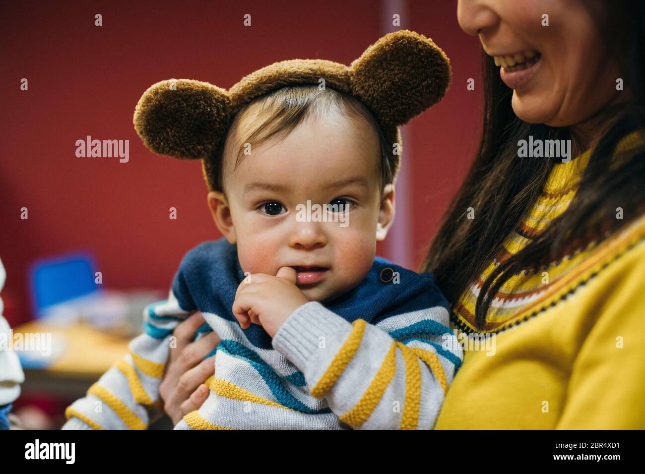 Portrait of a little boy being carried by his mother, he is wearing ...