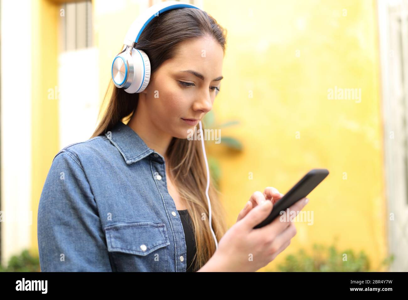 Woman walks listening to music selecting songs in a colorful street ...