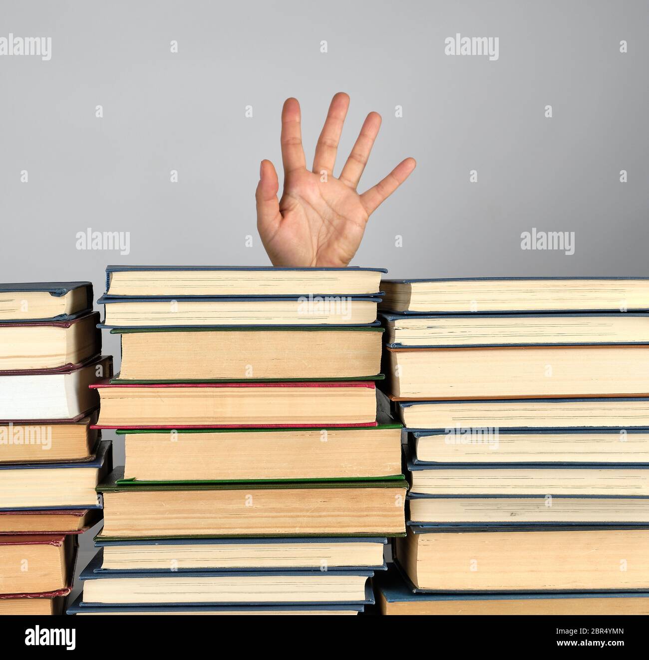 stack of different books on a gray background, one female hand stick ...