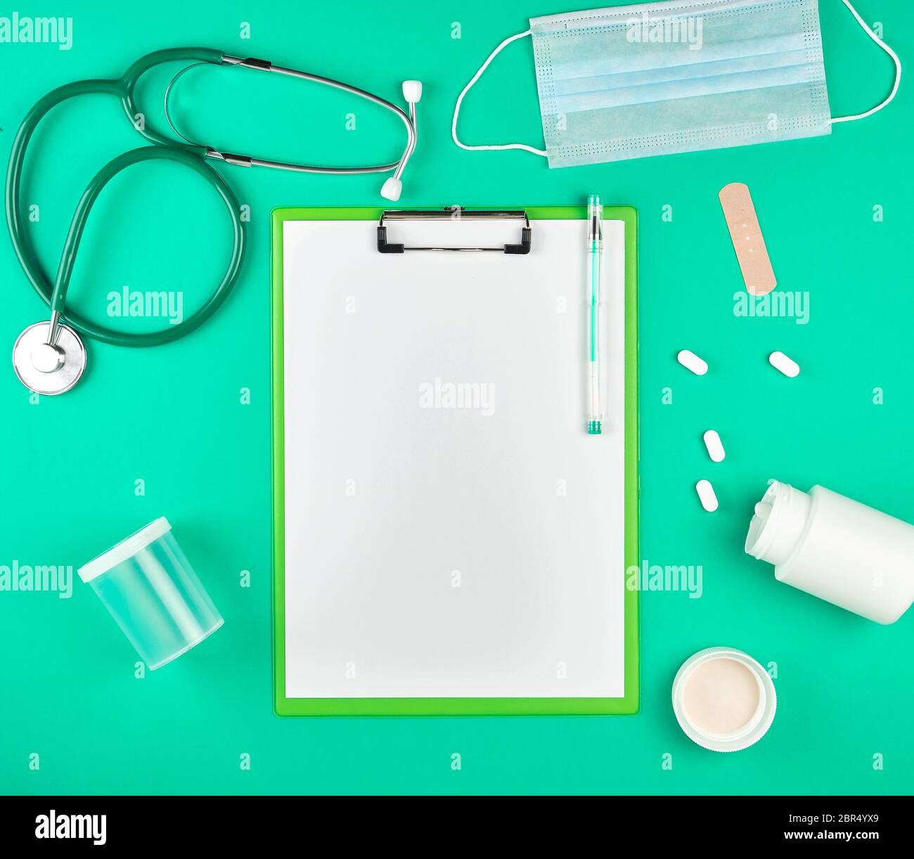 paper holder with empty white sheets, medical stethoscope, pills on a ...