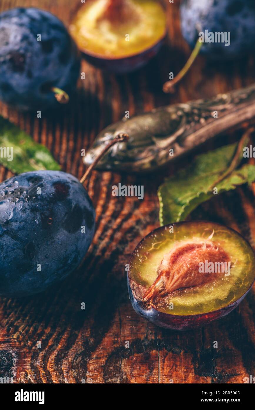 Ripe plums on wooden table with leaves, water drops and vintage knife ...