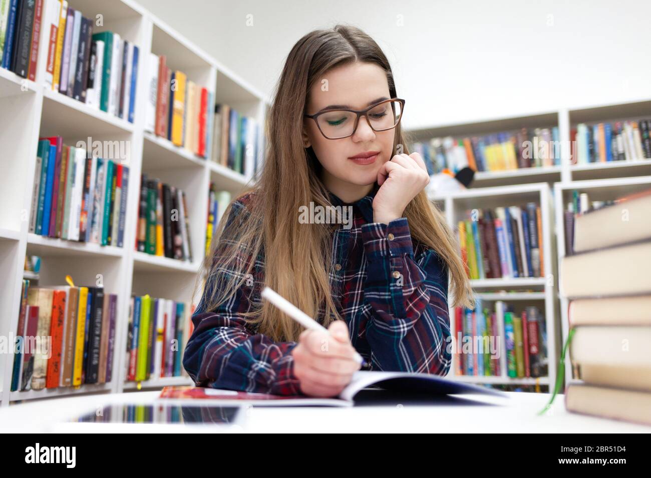 Girls writes in the library. Young student studying at the campus ...