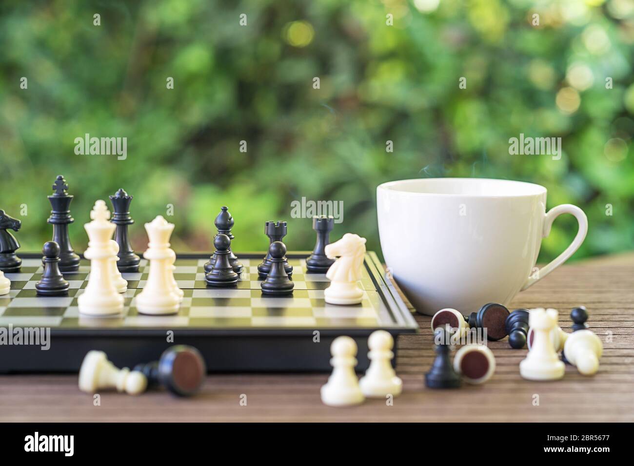 Cups of coffee on wood table with Chess board and pieces for relax time ...