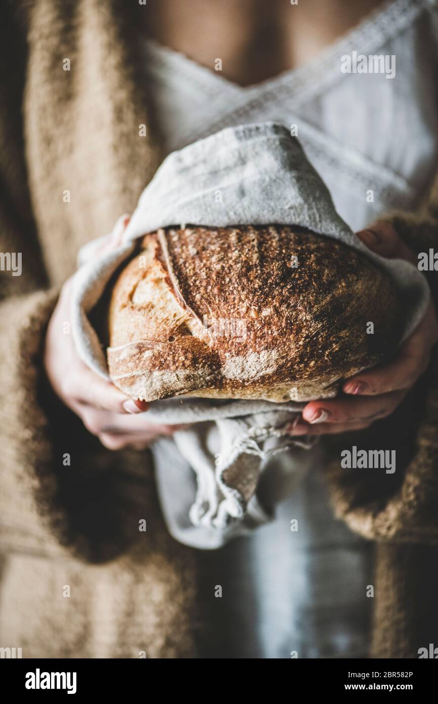 Woman holding freshly baked healthy rye Swedish bread round loaf in ...