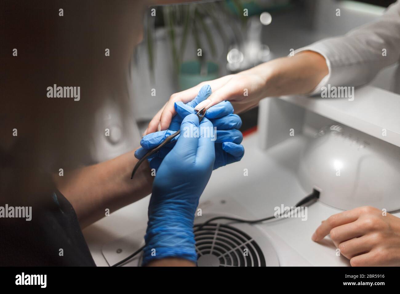 Manicurist cuts the cuticle on the client’s nails with nipper Stock ...
