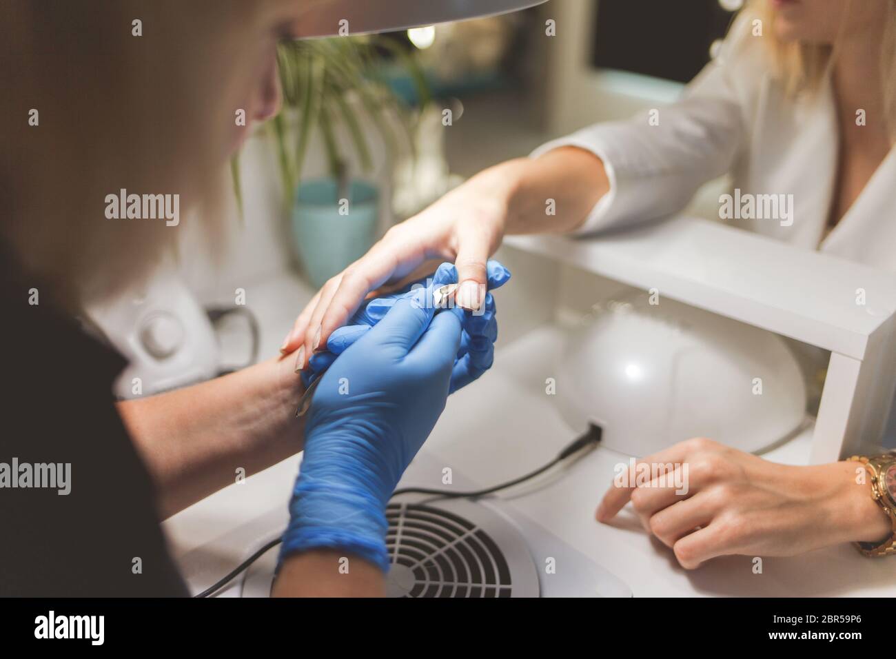 Manicurist cuts the cuticle on the client’s nails with nipper Stock ...