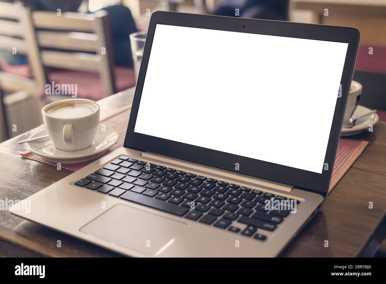Laptop mockup on coffee shop desk. Cup of coffee beside. White screen ...