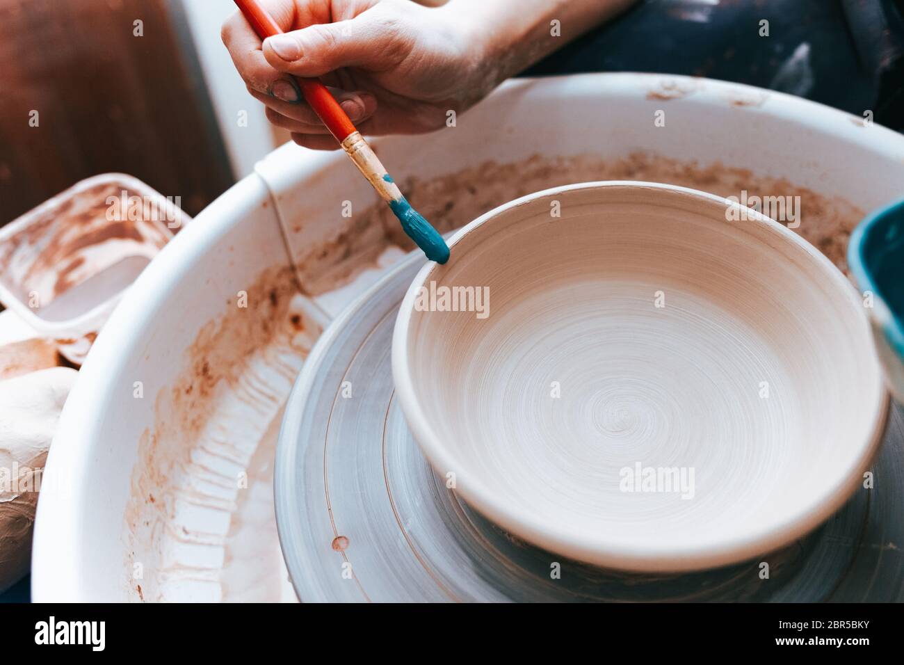 Professional potter works on painting plates in the workshop. Woman ...