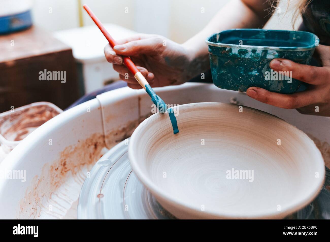 Professional potter works on painting plates in the workshop. Woman ...