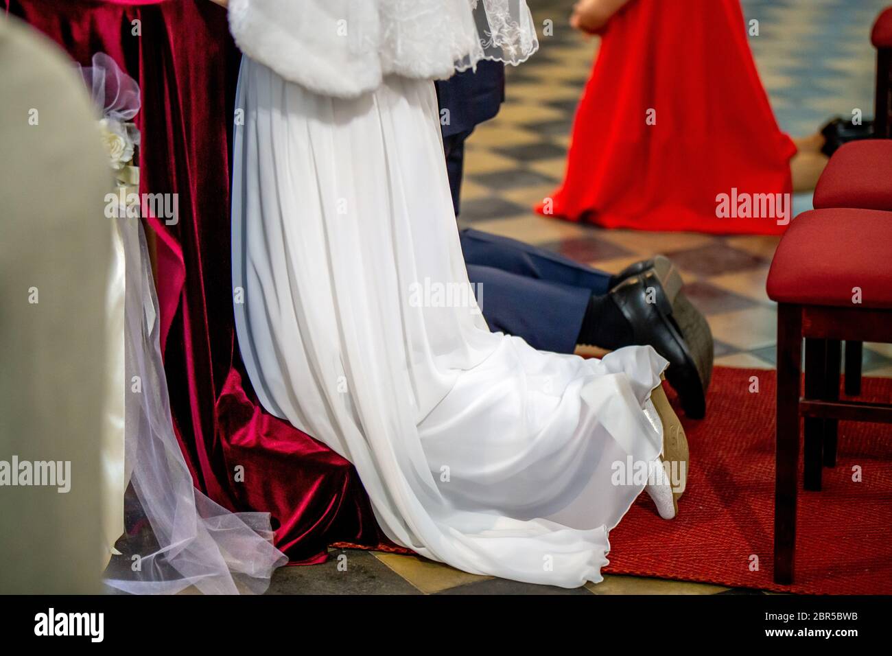 Bride and groom preparing for communion on knees at wedding ceremony in ...
