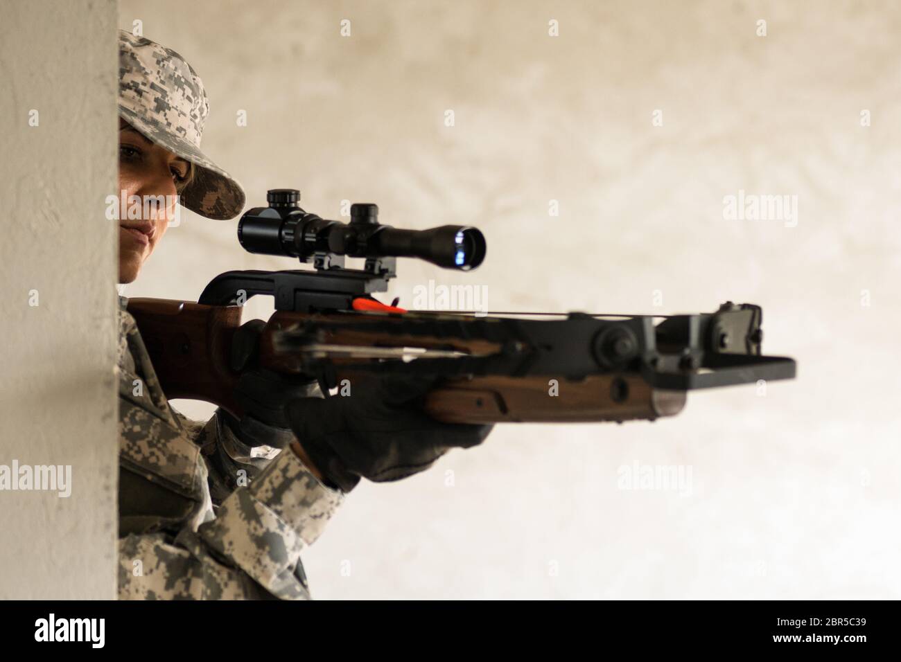 The female soldier in military uniform is holding a crossbow weapon ...