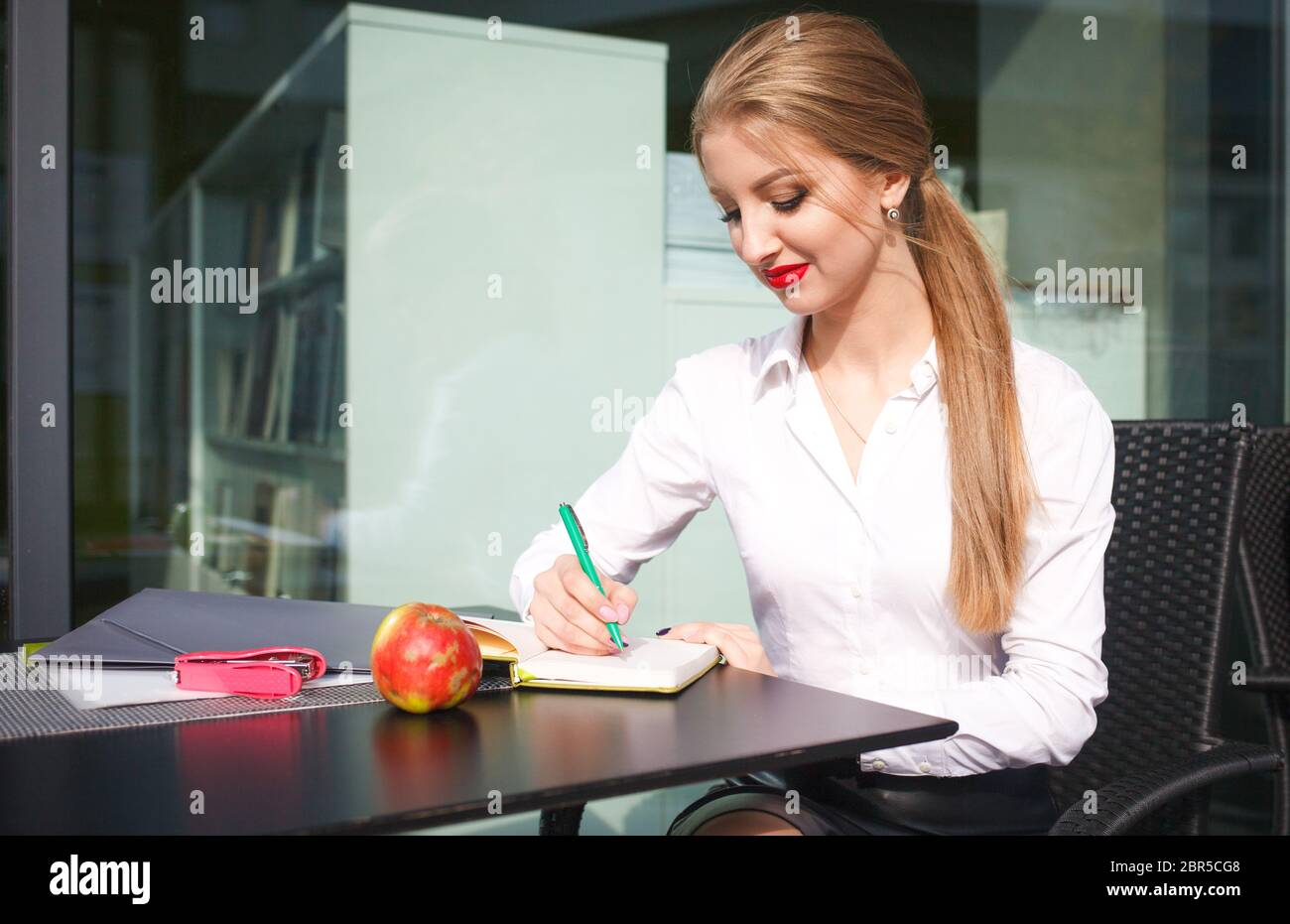 Young student girl writes a diary. Business woman with a pan in hand ...
