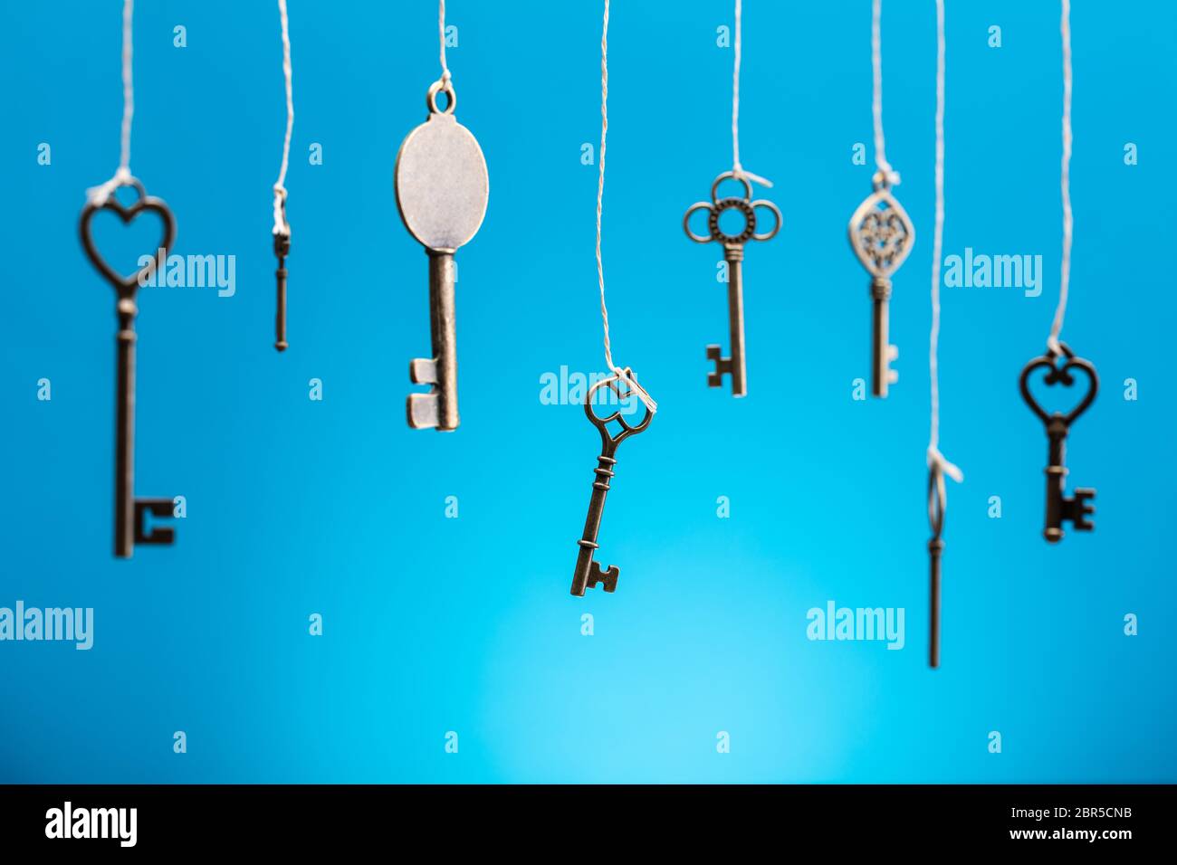 Old Keys Hanging With Strings In A Row Against Blue Backdrop Stock ...