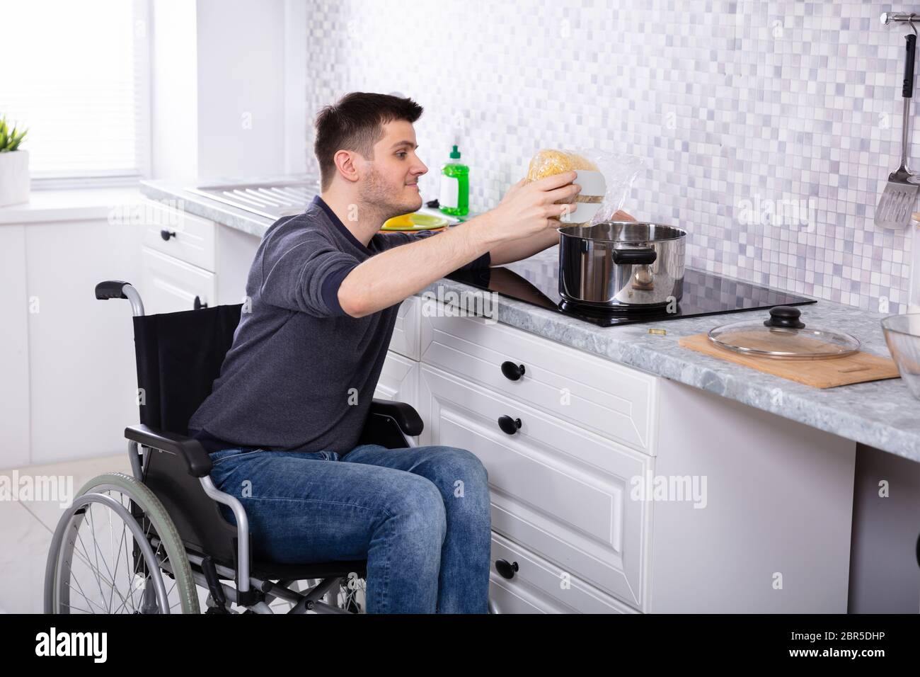 Smiling Young Handicapped Man Sitting On Wheelchair Preparing Food In ...