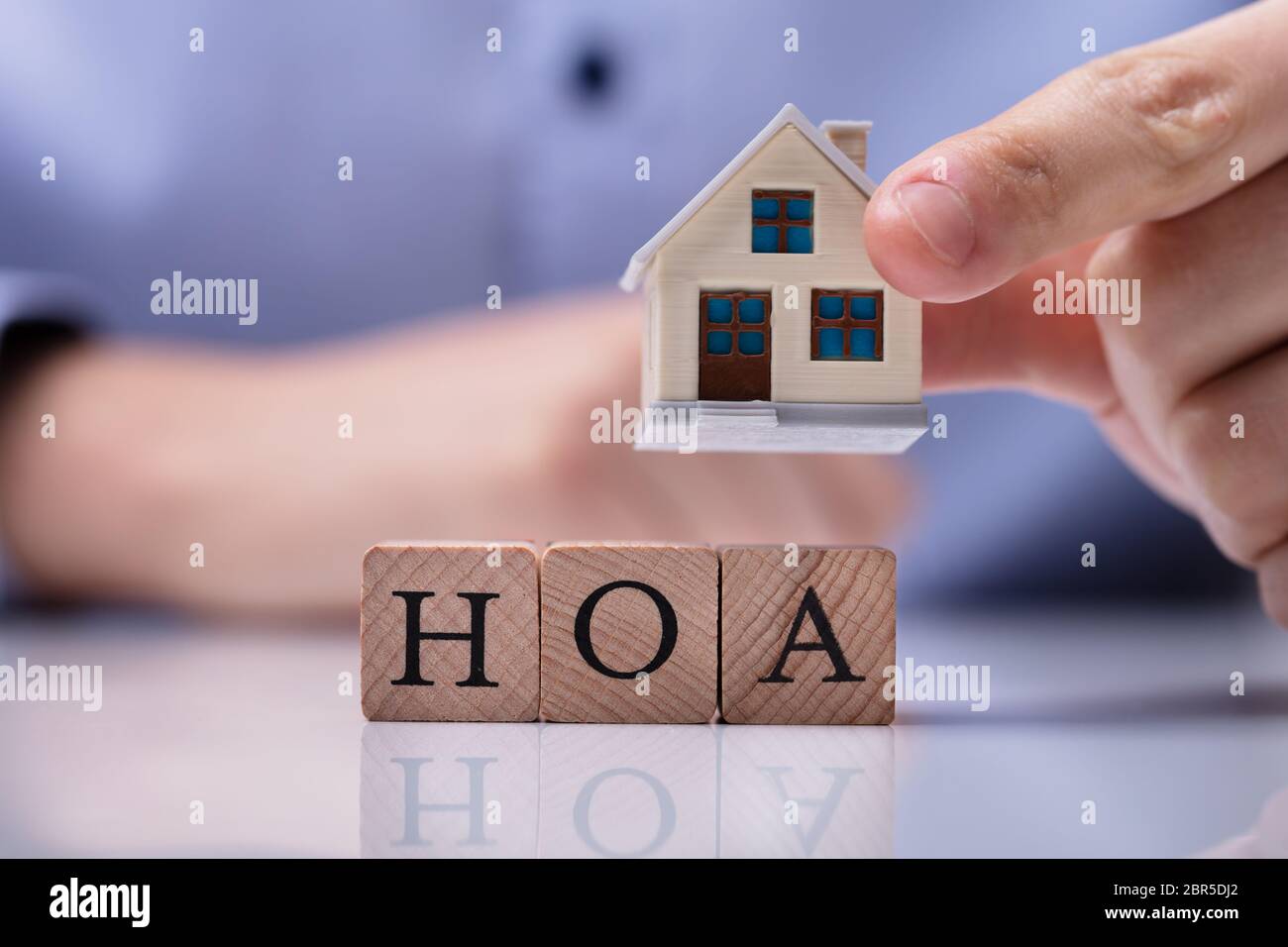Businessman's Hand Placing House Models On Wooden HOA Cubic Blocks Over ...