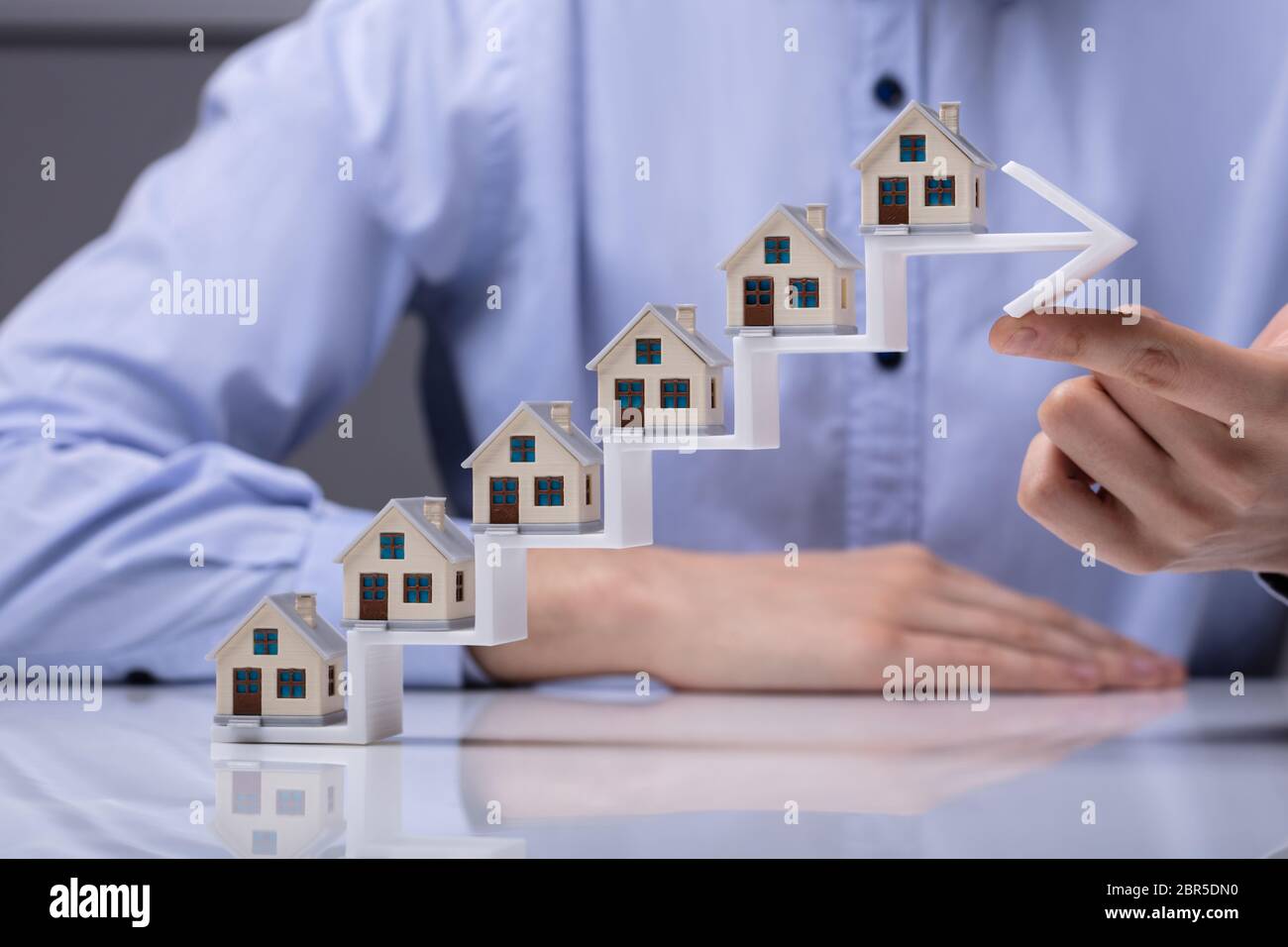 Businessman Supporting Miniature House Models On Staircase Stock Photo ...