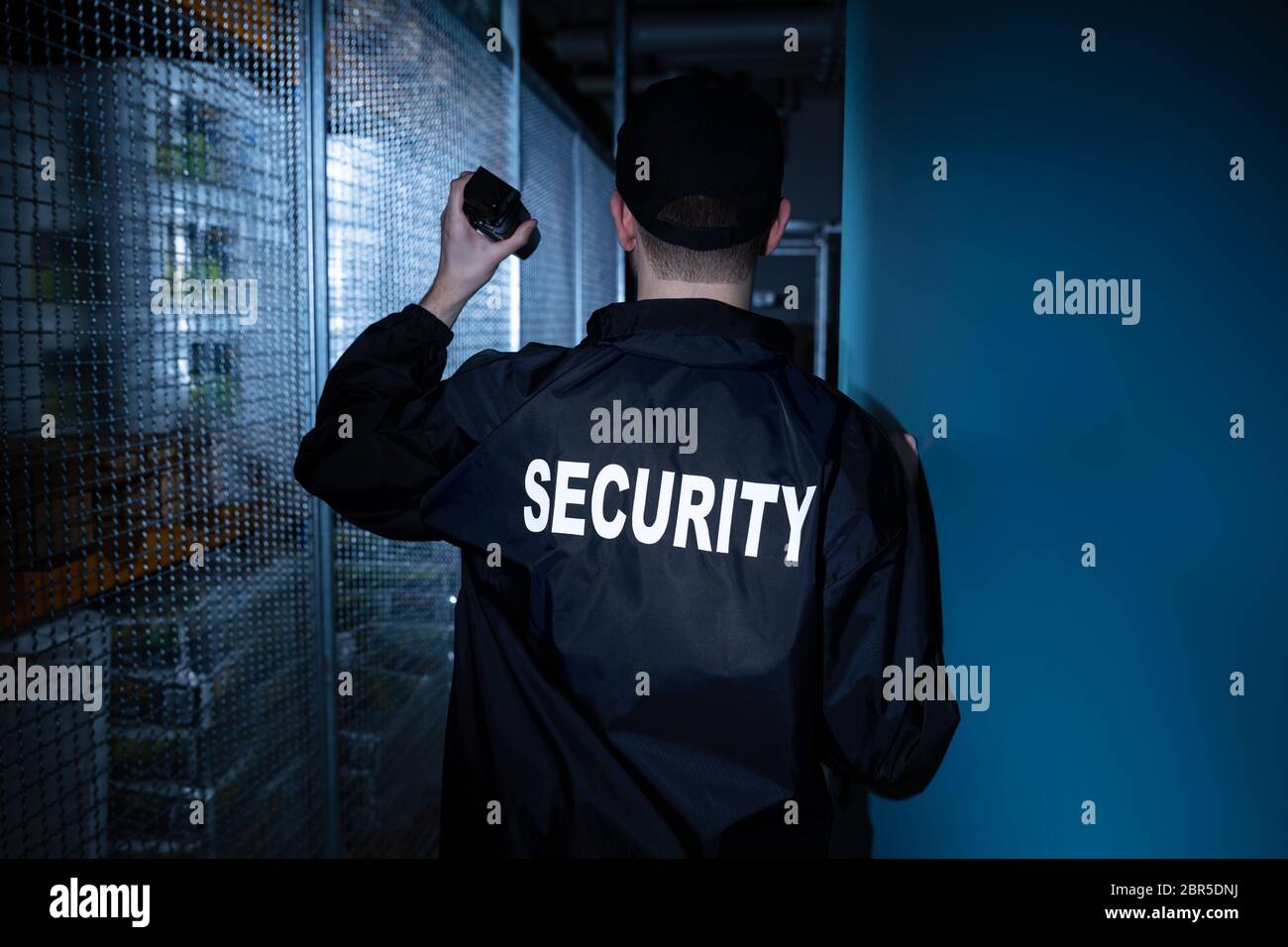 Rear View Of A Security Guard Standing In The Warehouse Holding ...