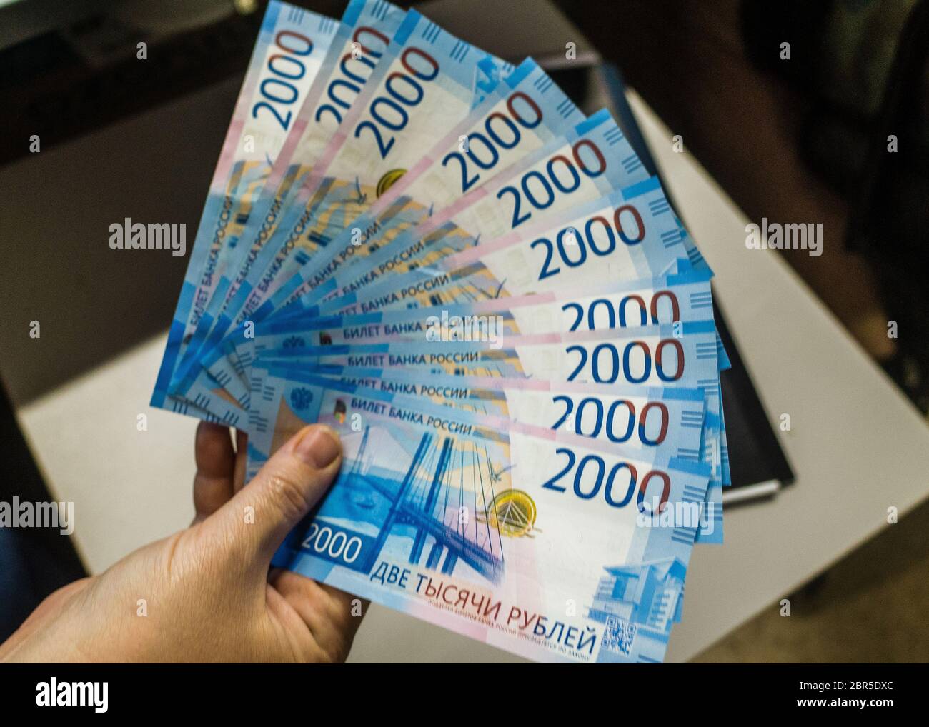 A fan of banknotes of 2000 Russian rubles in the hand of a young man ...