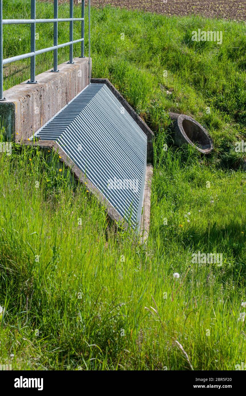 a small flood channel with metal grid and concrete pipeline to prevent ...