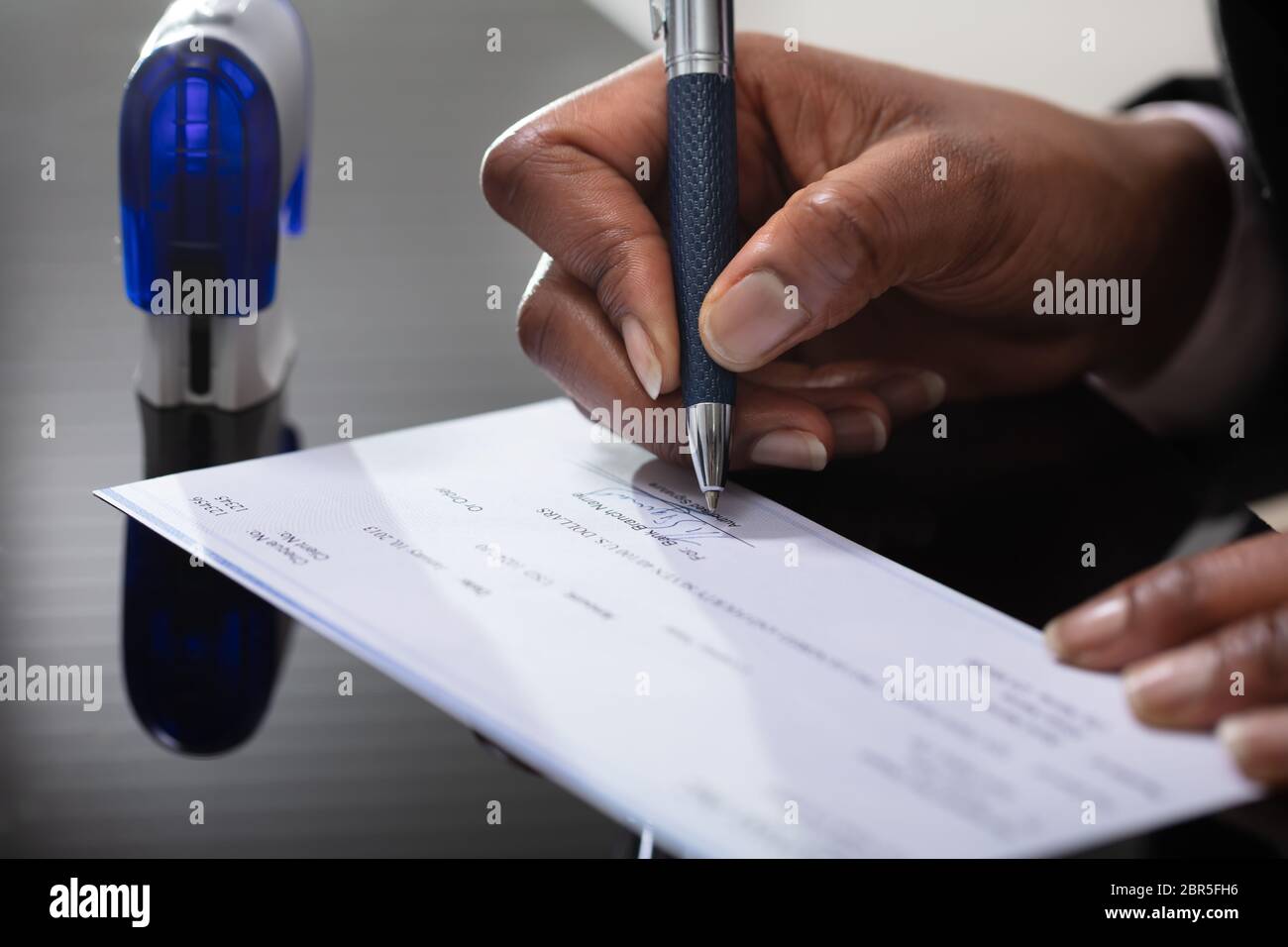 Photo Of Businessperson's Hand Signing Cheque With Pen Stock Photo - Alamy