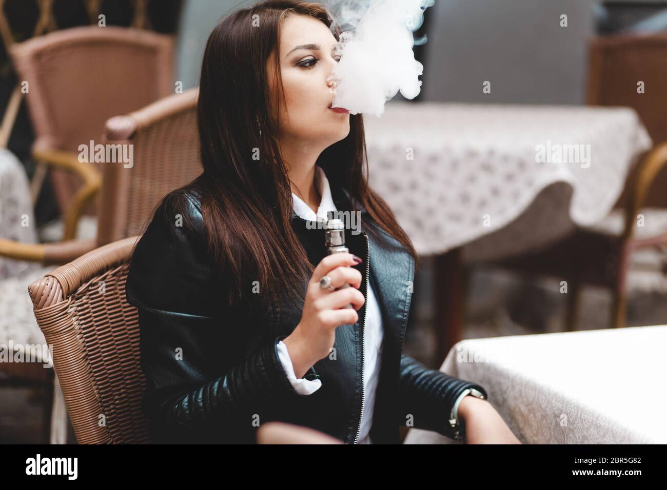 Pretty lady holding an electronic cigarette in her hand while sitting ...