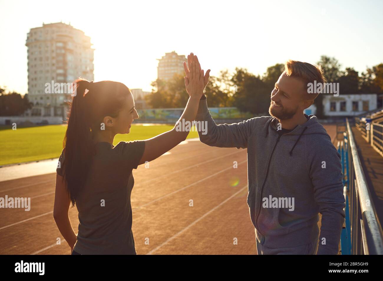 A young couple of athletes raised their hands up in the morning at dawn ...