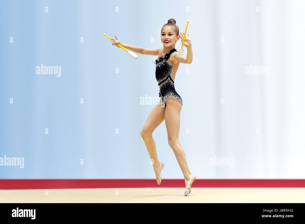 Little talented gymnast girl performs in a rhythmic gymnastics ...