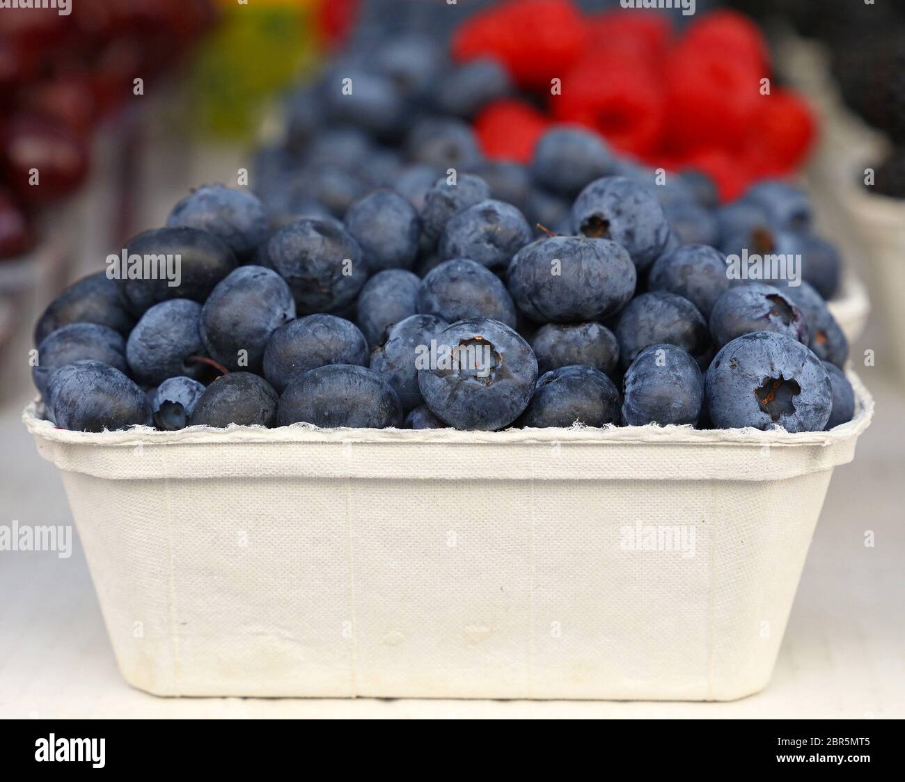 Close up fresh blueberry berries in paper container on retail display ...