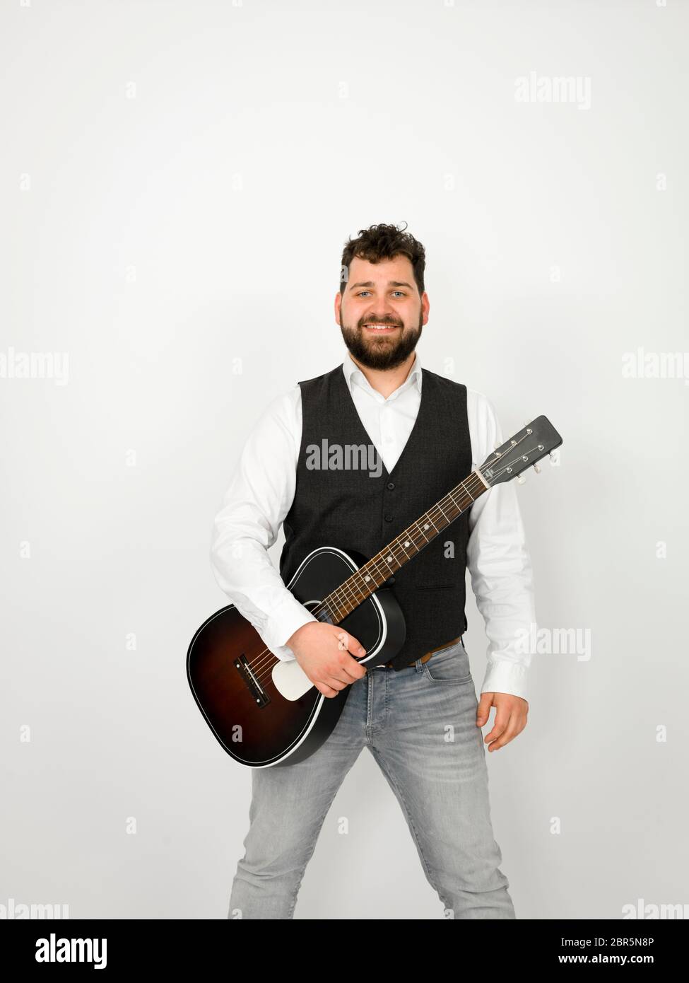 man with black hair and beard playing and singing with acoustic guitar ...