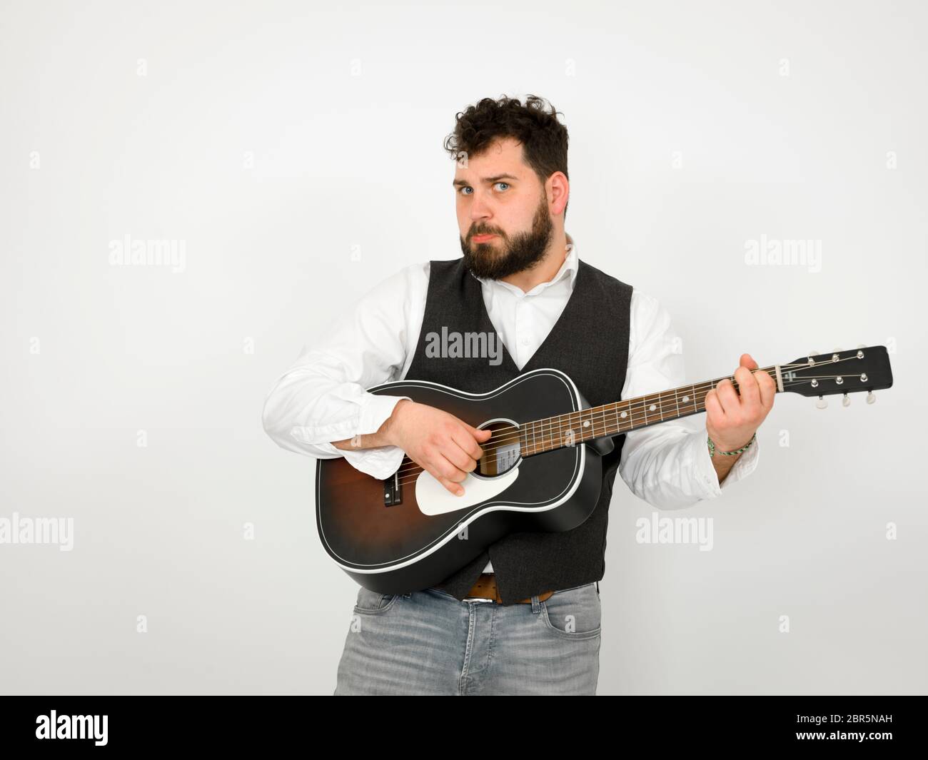 man with black hair and beard playing and singing with acoustic guitar ...