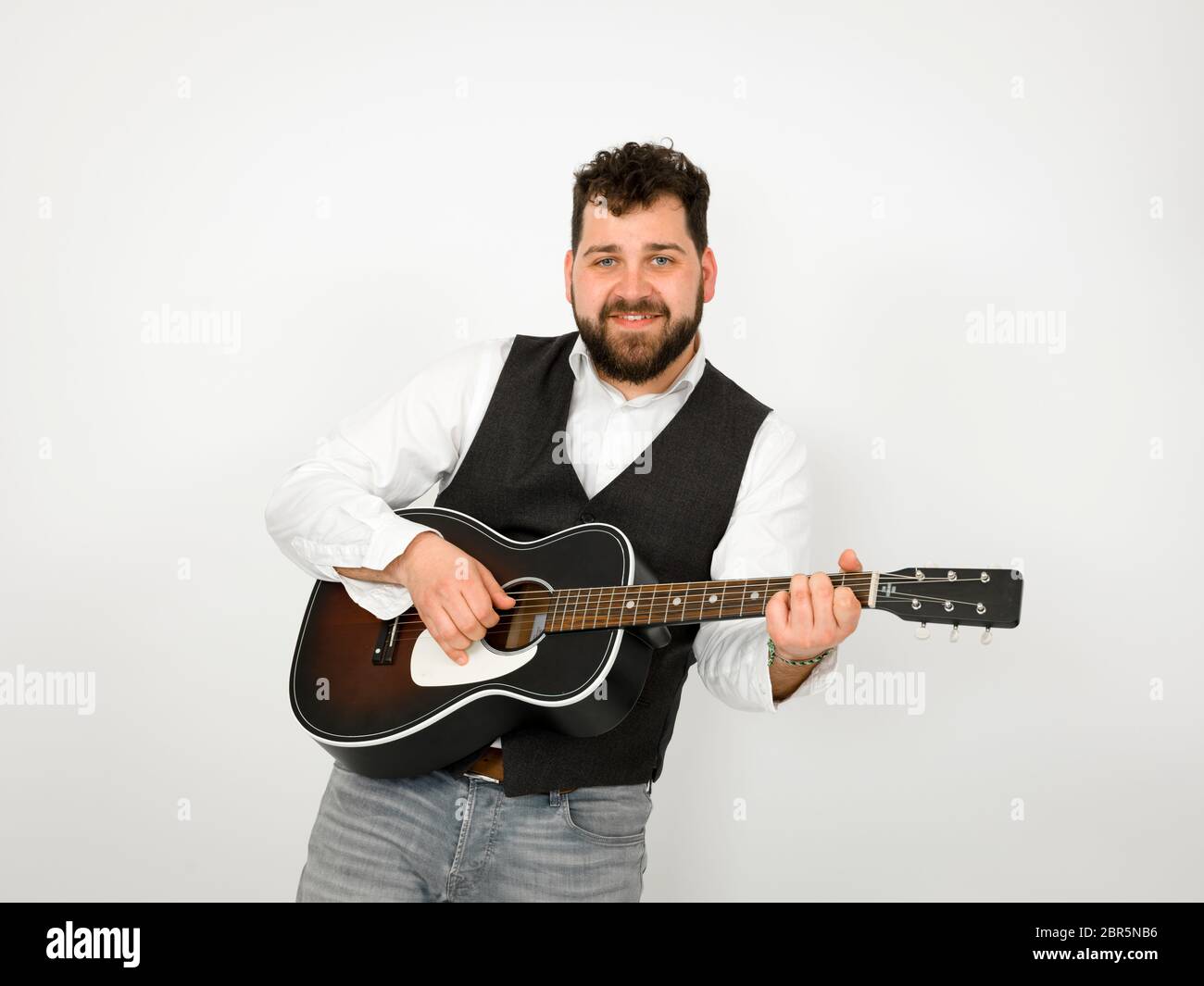 man with black hair and beard playing and singing with acoustic guitar ...
